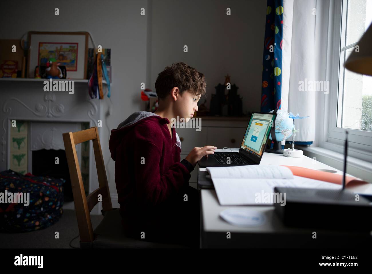 10-year old boy attempting to do his homework on his school laptop ...