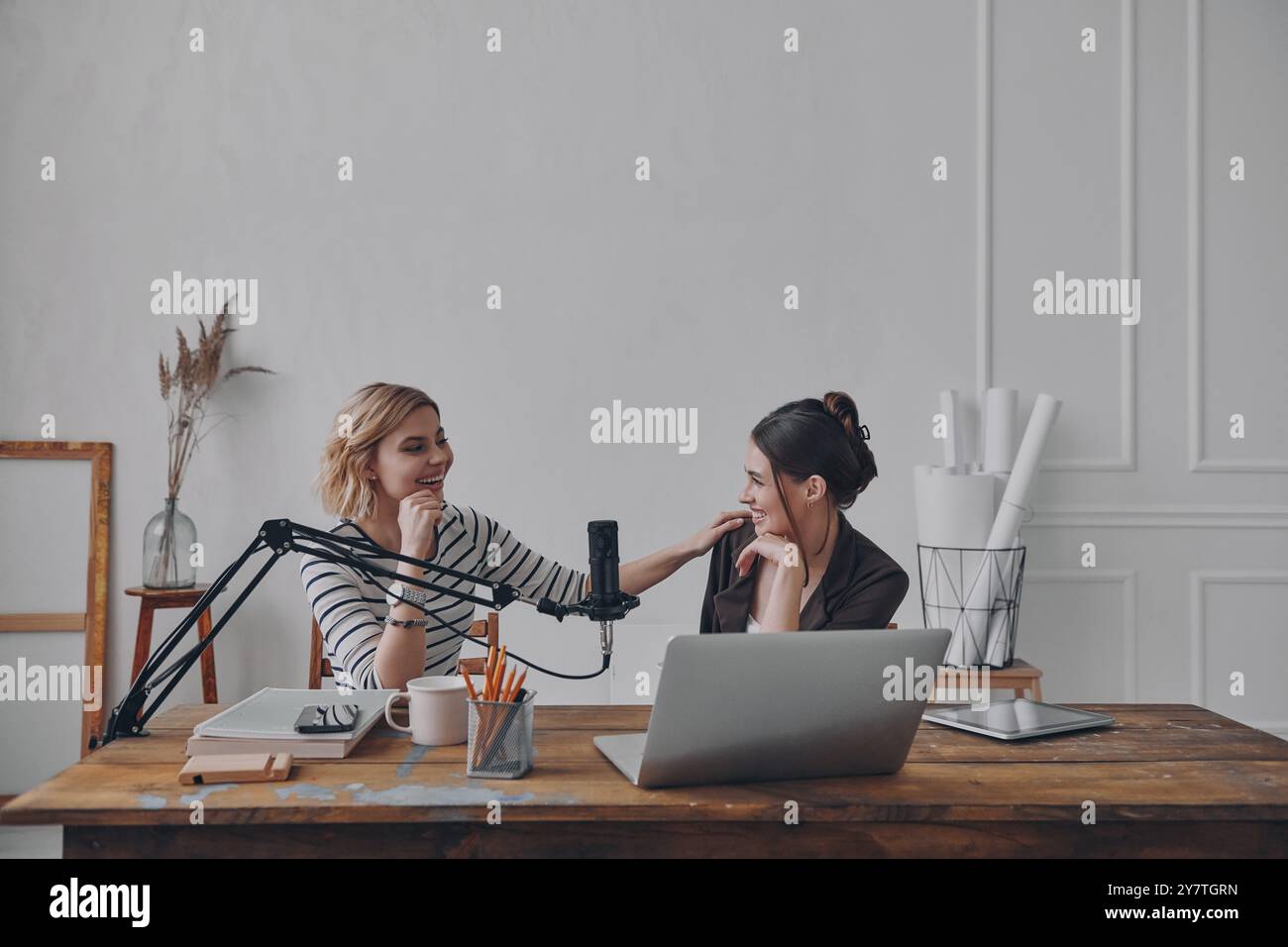 Two happy young women communicating and smiling while broadcasting in ...