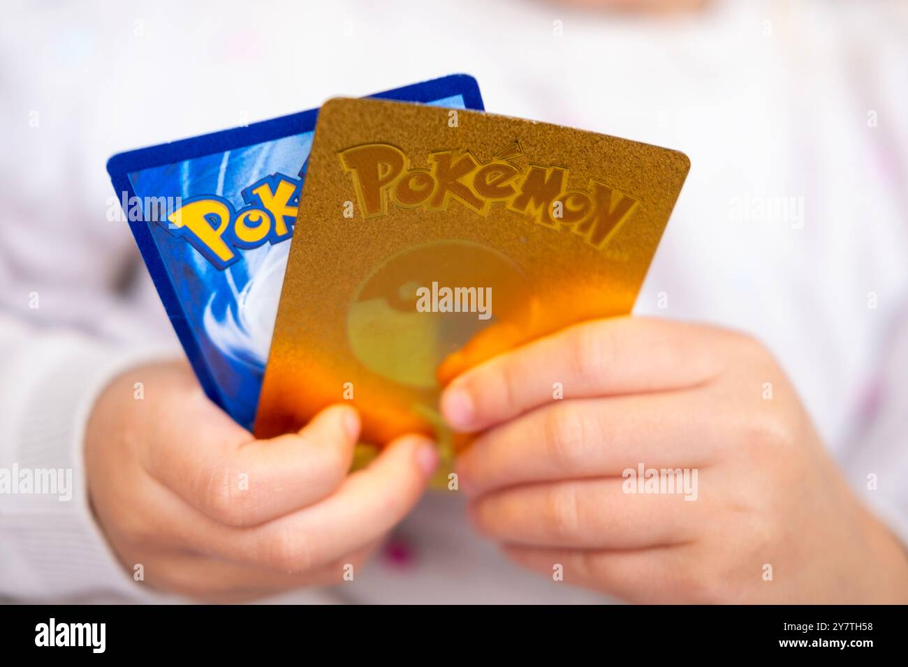 child's small hands hold favorite Pokémon card, young fan eagerly ...