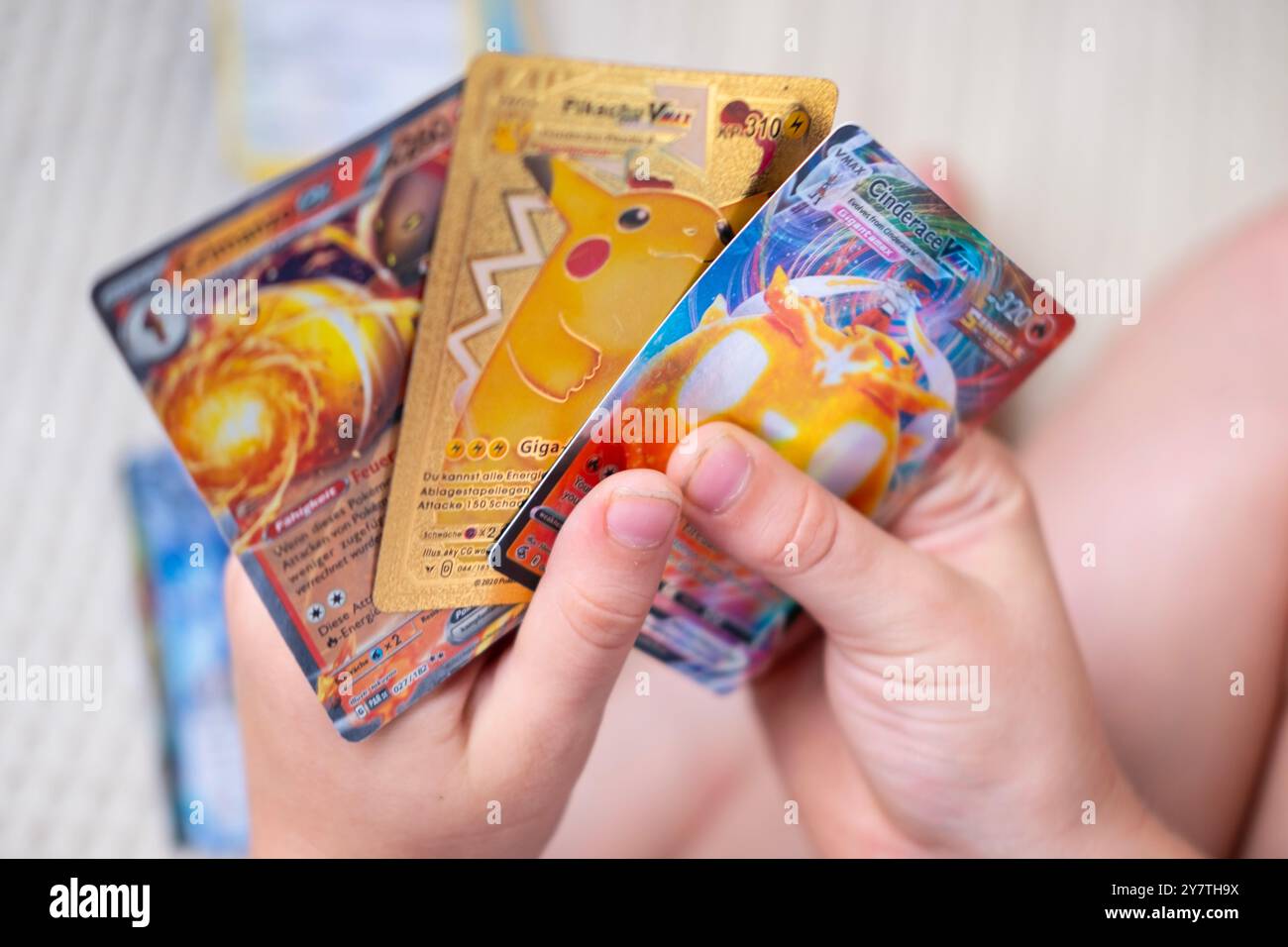 child's small hands hold favorite gold Pikachu, Pokémon card, young fan ...