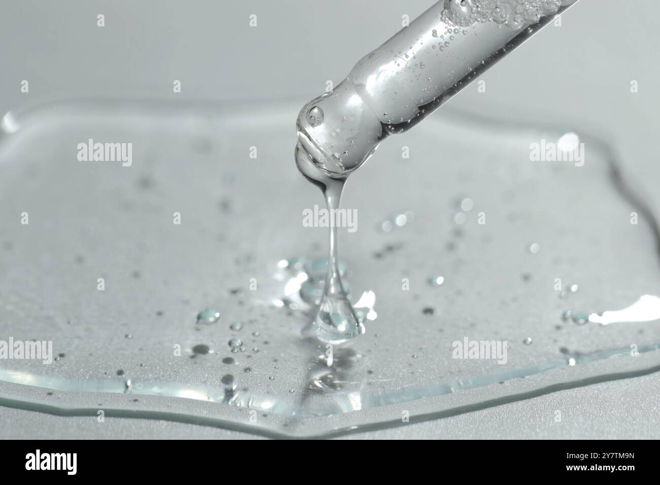 Dripping cosmetic serum from pipette on light background, closeup Stock ...