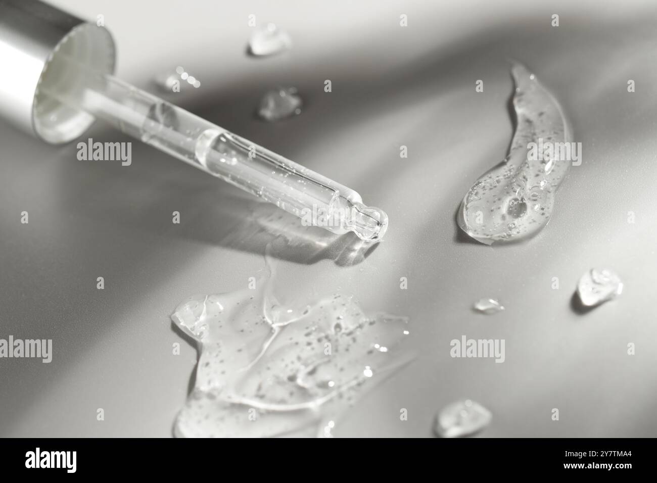 Dripping cosmetic serum from pipette on grey background Stock Photo - Alamy