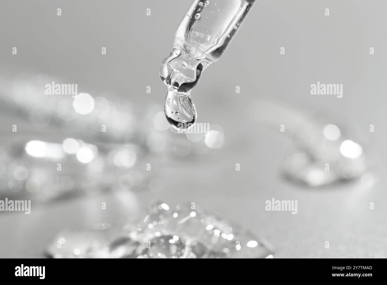 Dripping cosmetic serum from pipette on grey background, closeup Stock ...