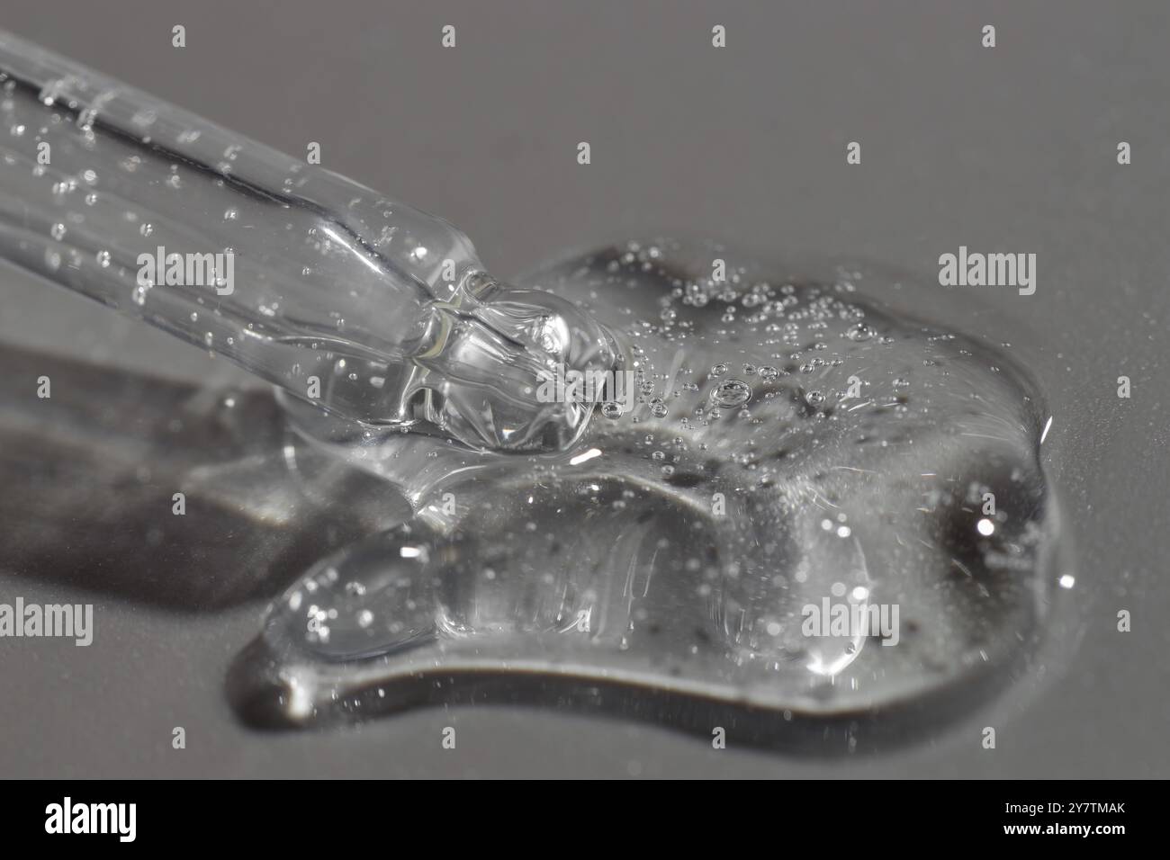 Dripping cosmetic serum from pipette on grey background, closeup Stock ...