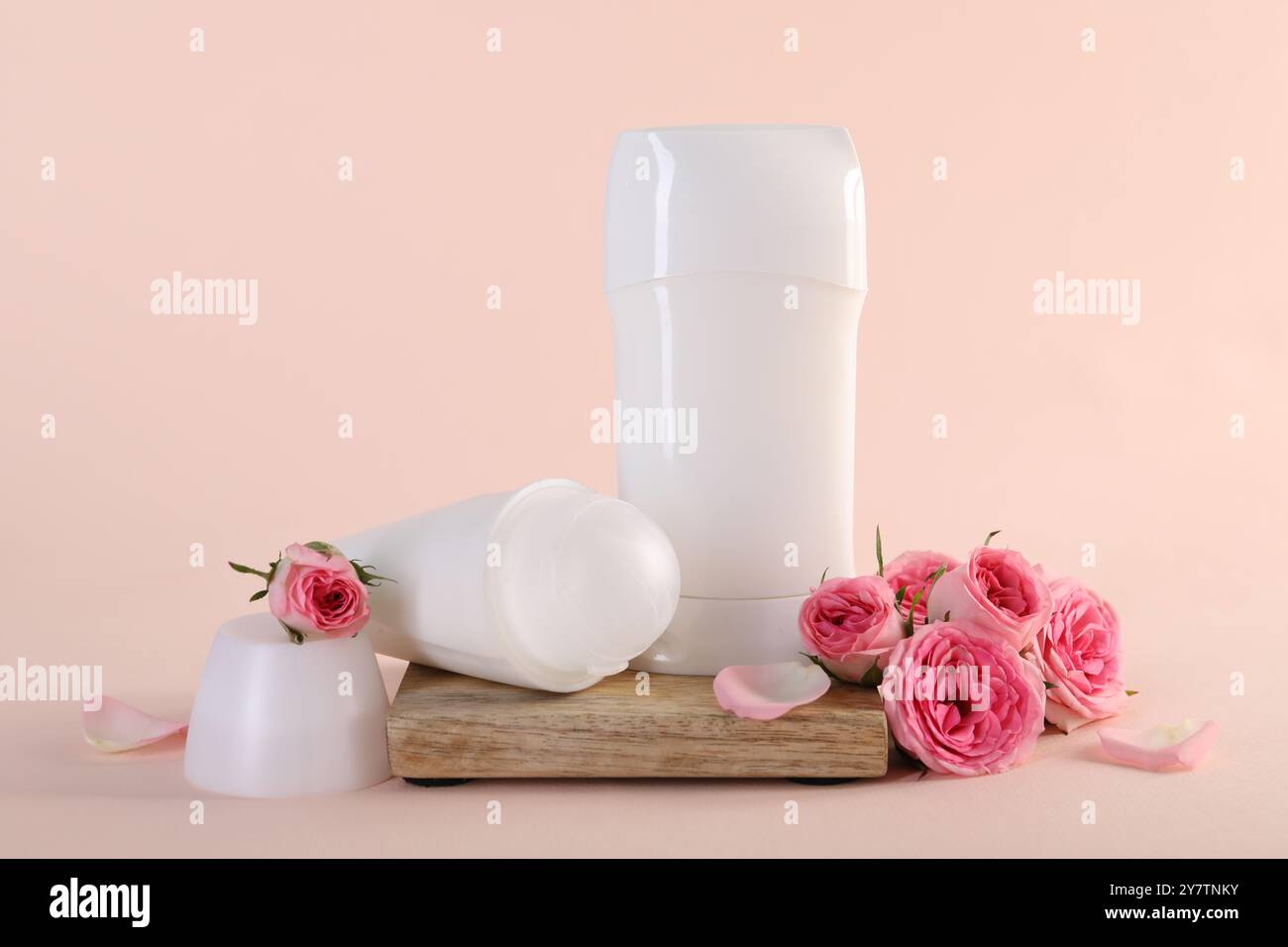 Different deodorants and beautiful rose flowers on beige background ...
