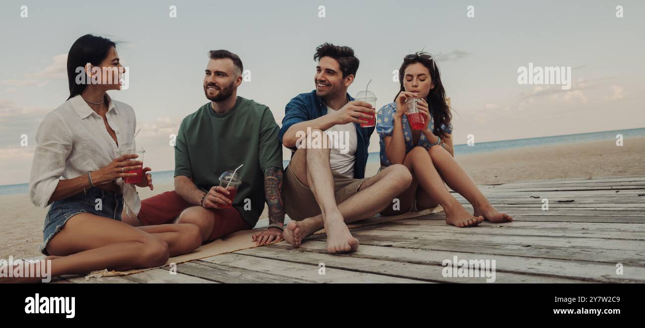 Four young people talking and smiling while enjoying refreshing ...