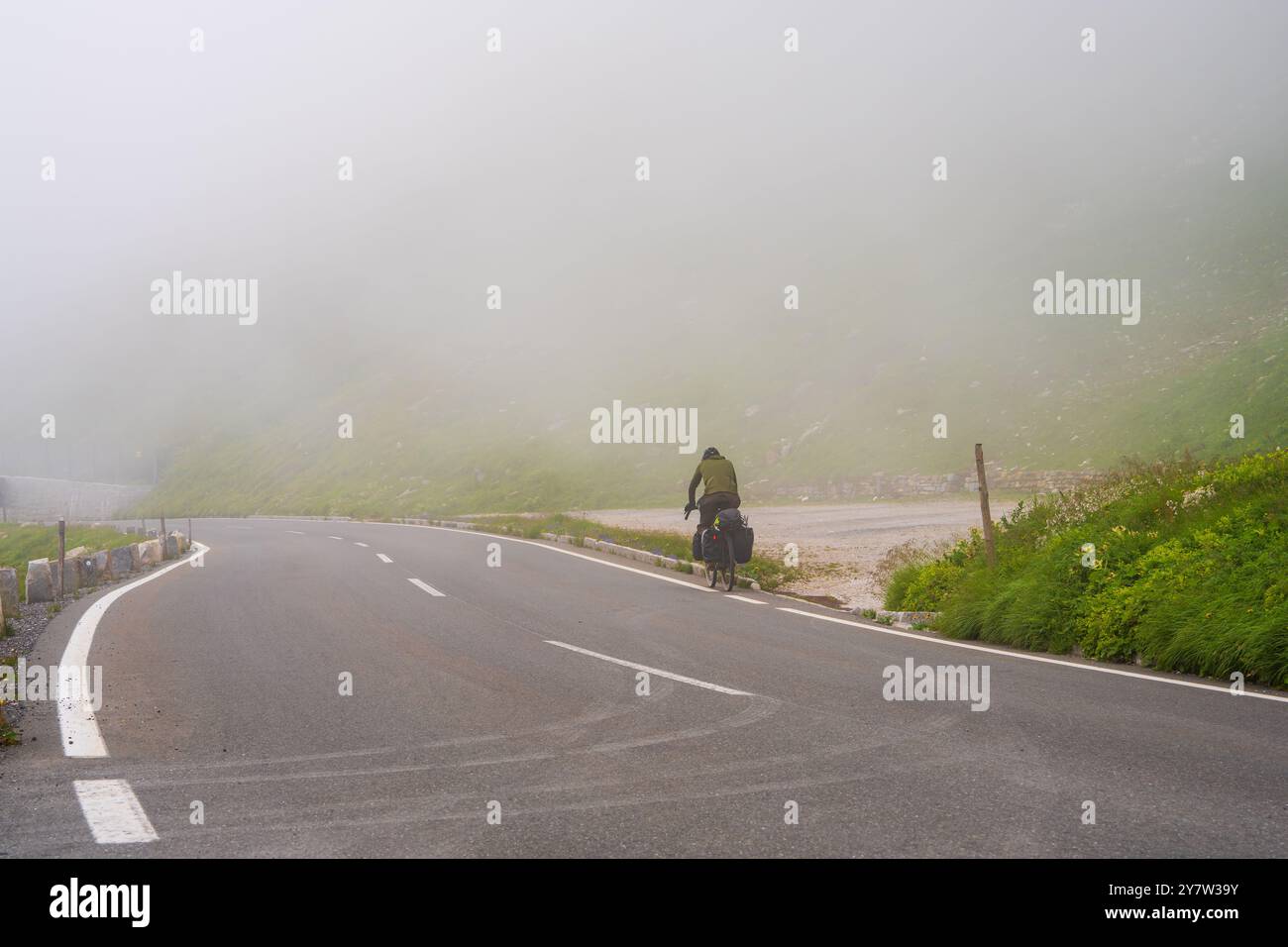 Very heavy fog on mountain road. Cyclist with luggage rides on ...