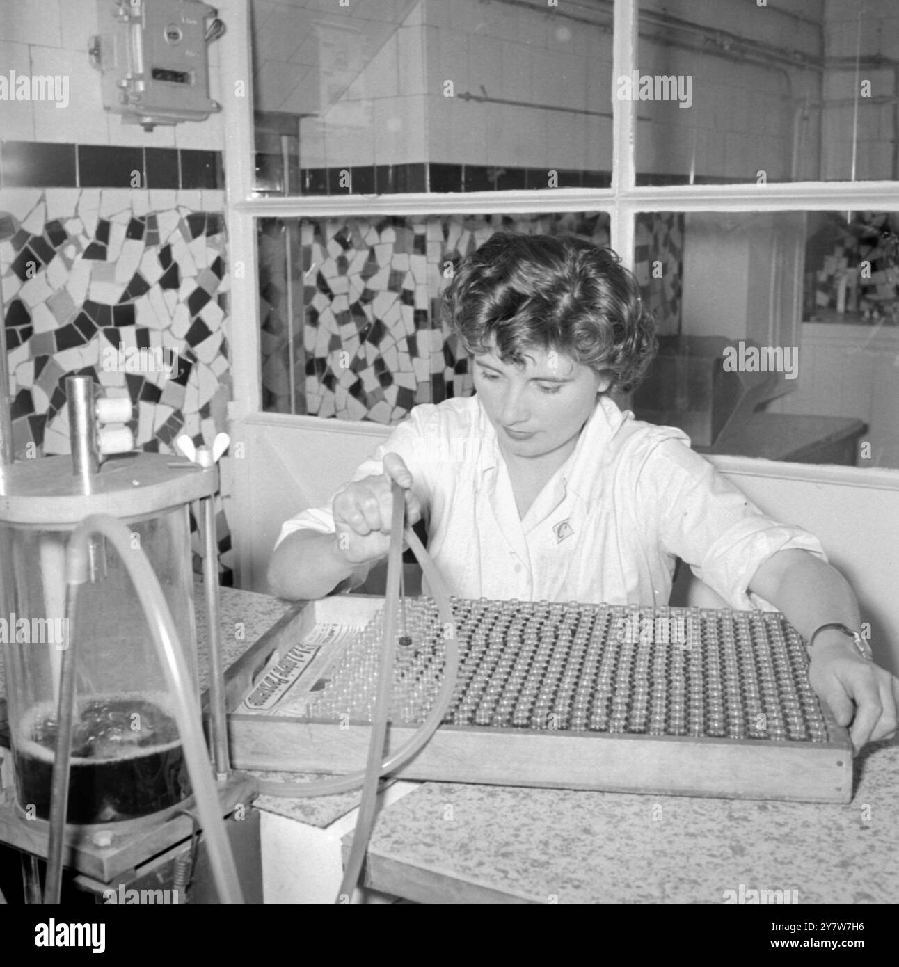 France - 1955A woman worker uses a pressure filler to bottle perfume in ...