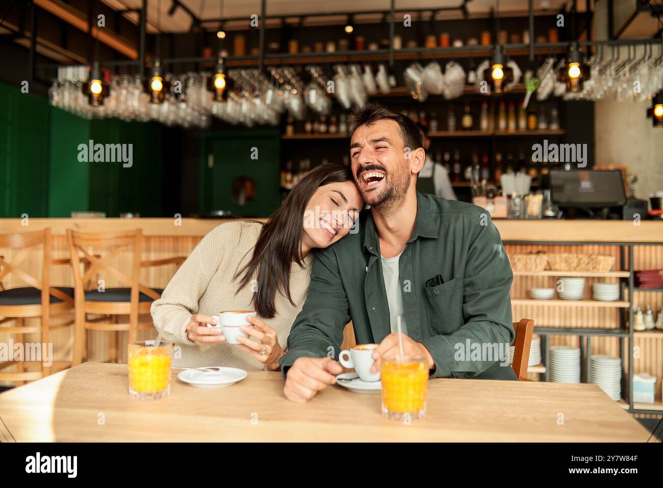 Couple shares a joyful moment at a stylish café, sipping coffee and ...