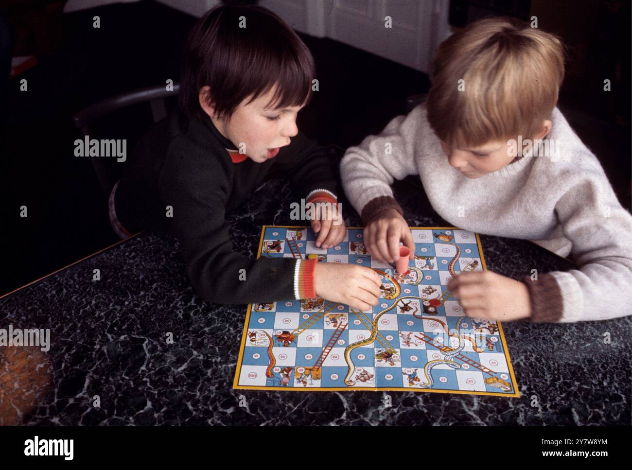 Two boys playing the snakes and ladders board gameUndated Stock Photo ...