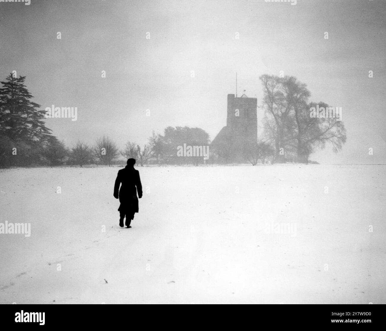 A man walking along the snow covered field to Nurstead Church , Kent ...