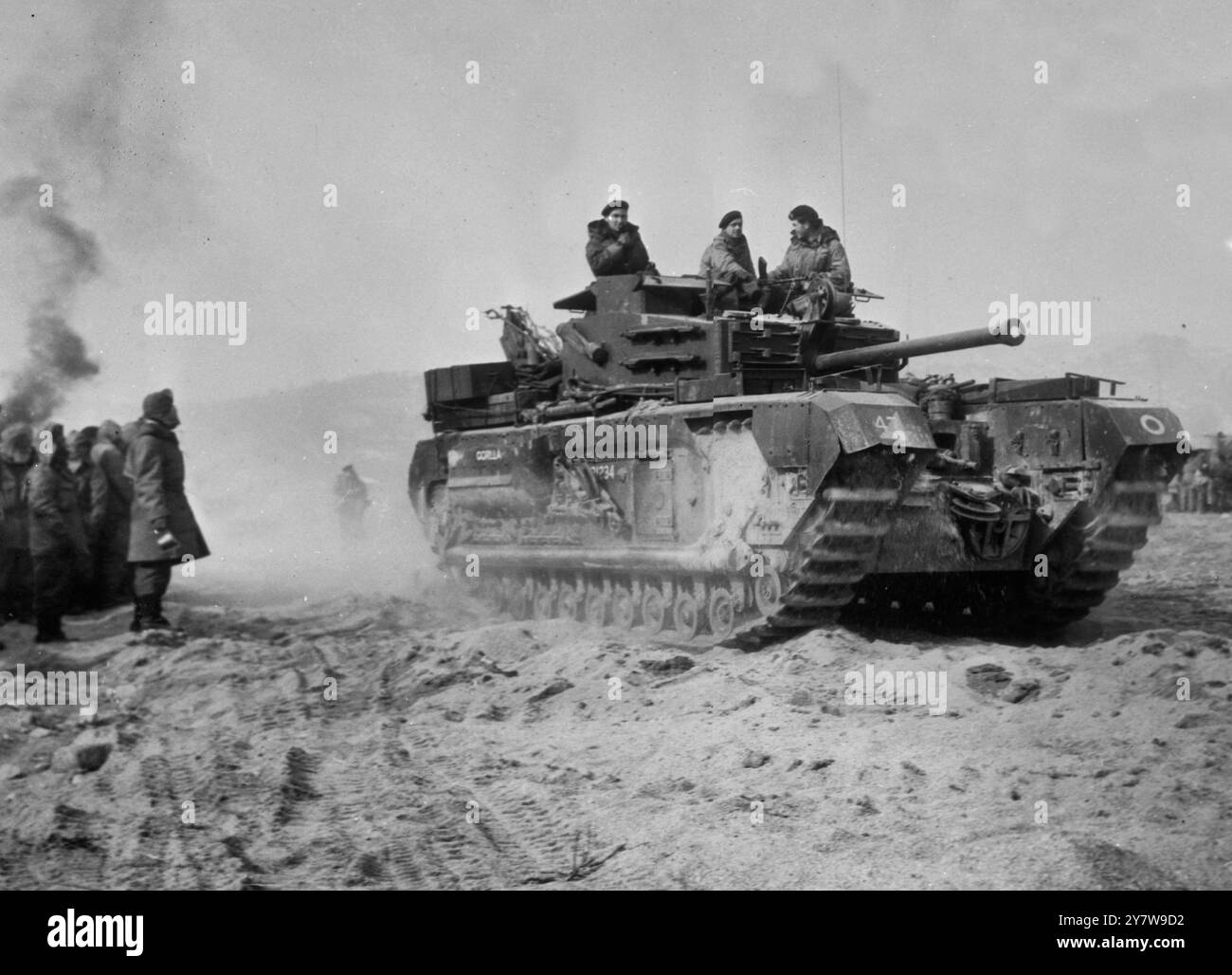 A British Churchill flame thrower tank, it's crew riding on top, moves ...