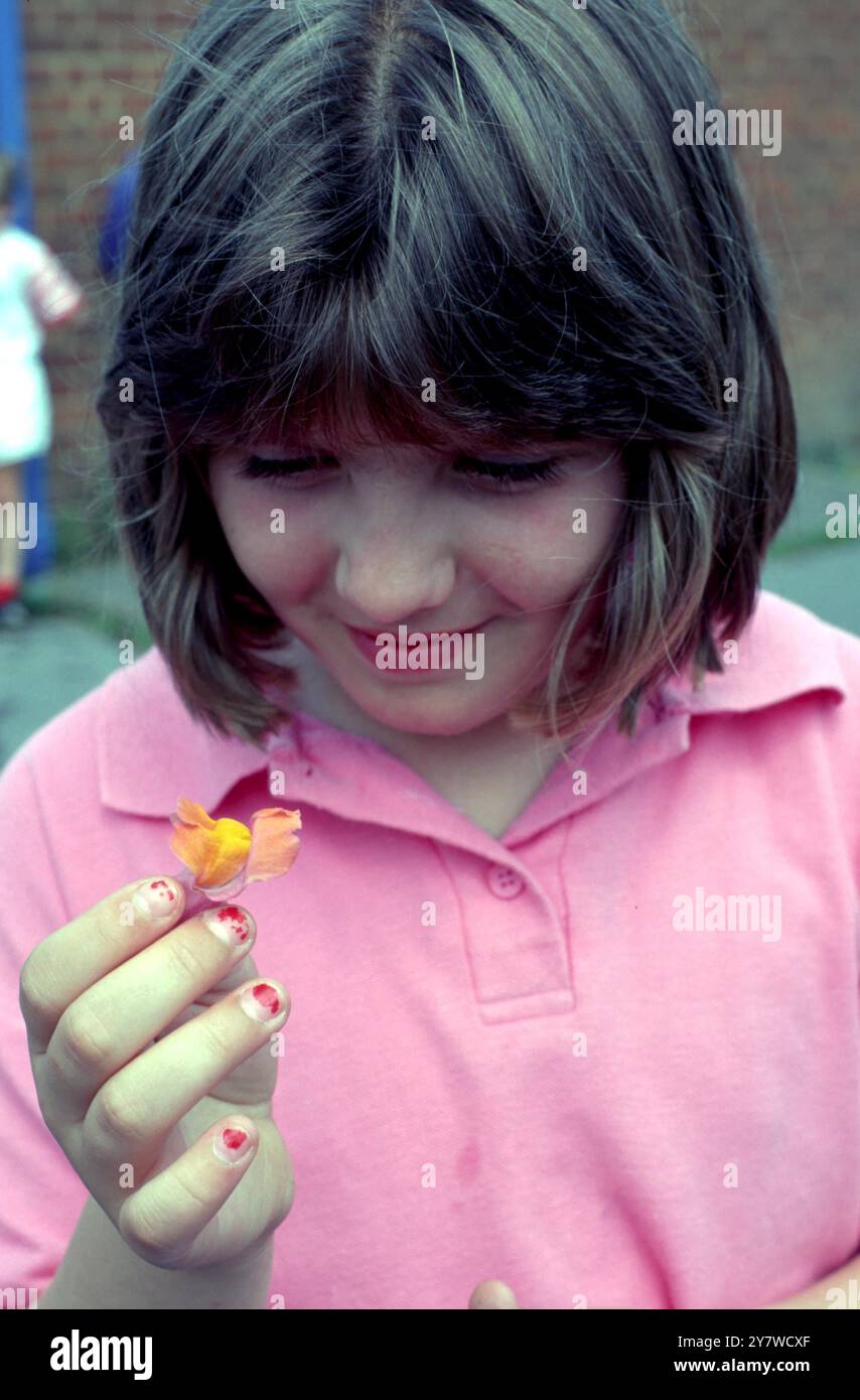 Little girl studying a snapdragon flower Stock Photo - Alamy