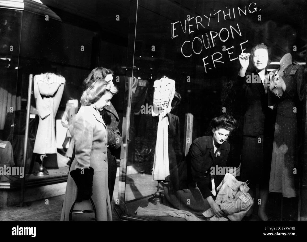 Girls rearrange the shop window in a West end store and write the good ...