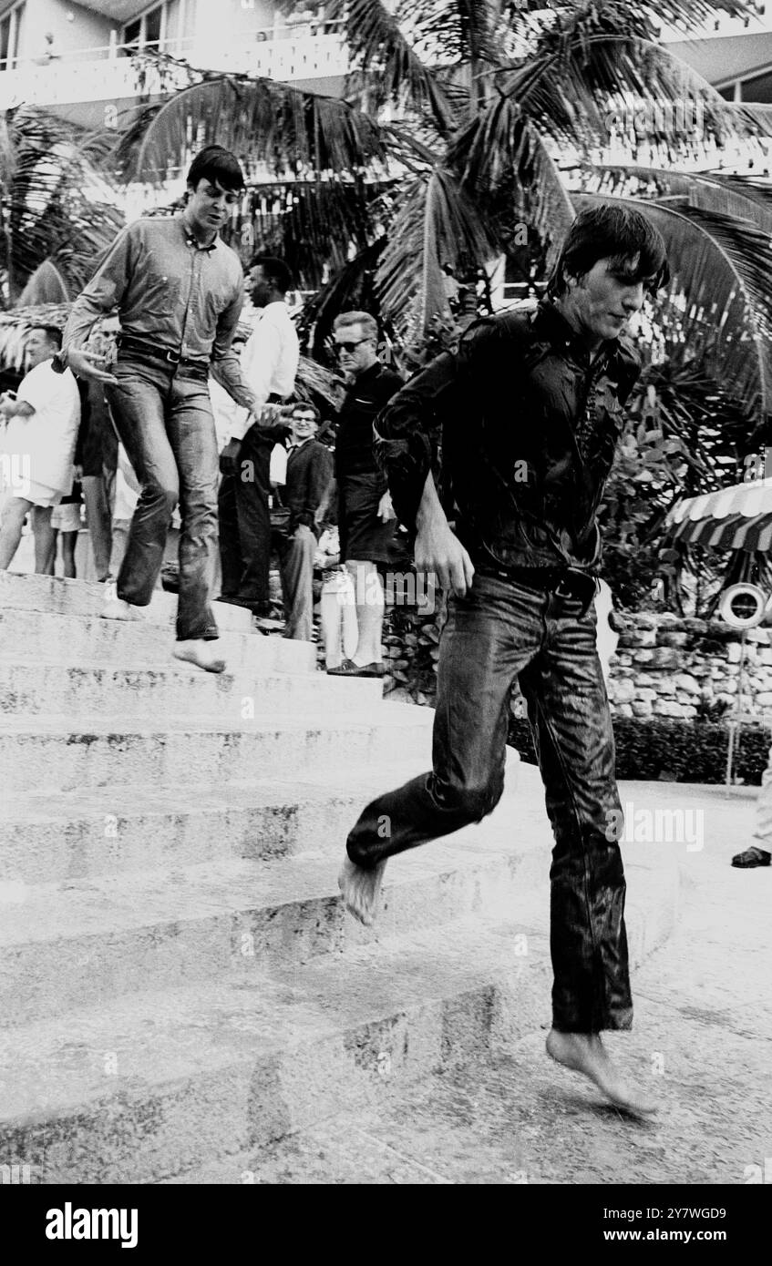 Paul McCartney (left) and George Harrison run along dripping wet after ...