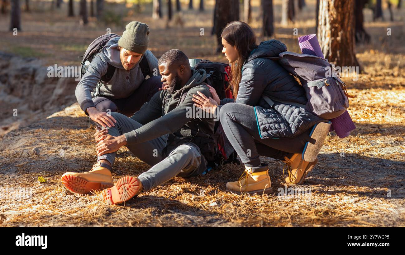 Friends helping black guy with injured leg, hiking at forest Stock ...
