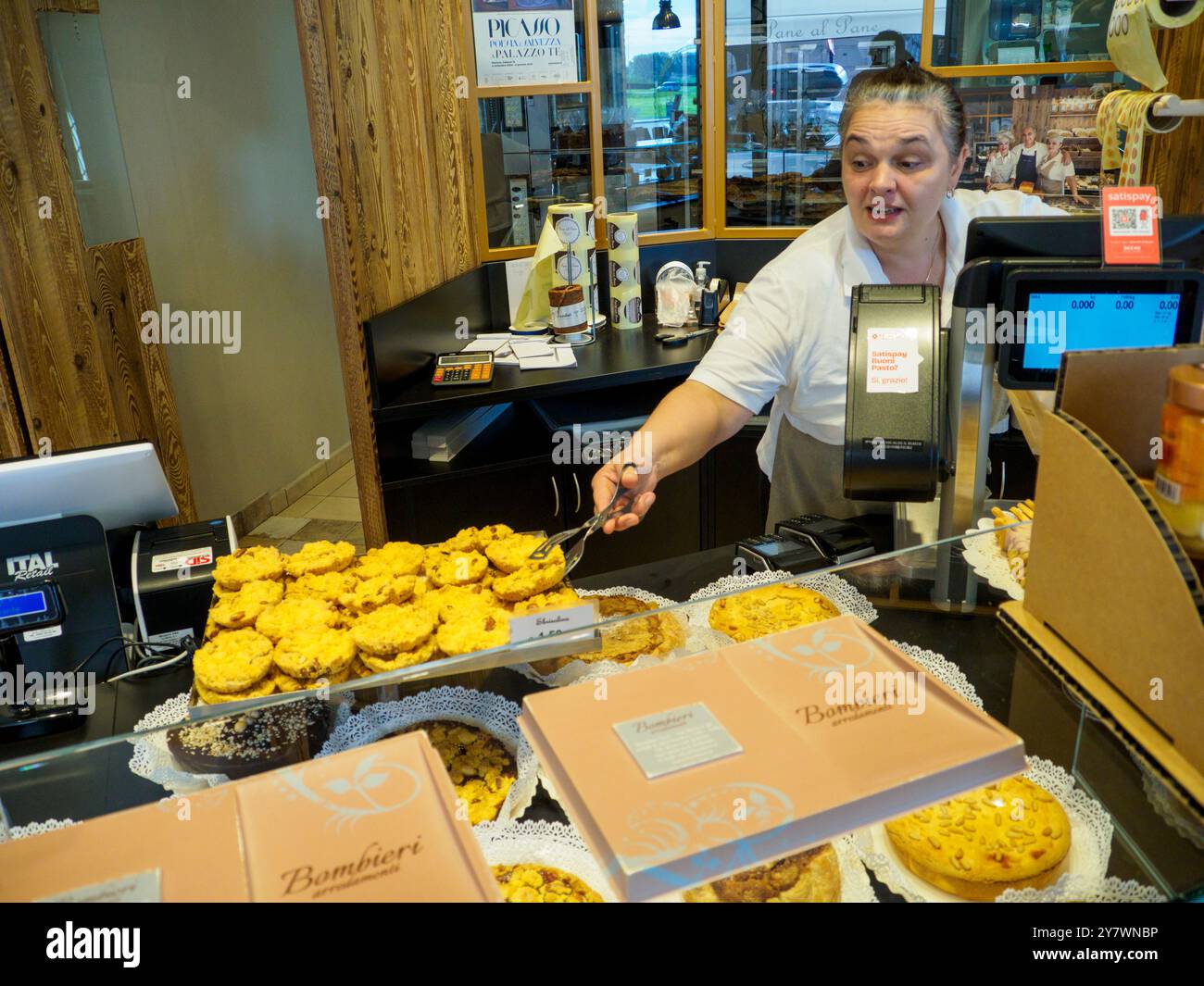 Mantua, Italy September 30th 2024 A smiling saleswoman is using tongs ...