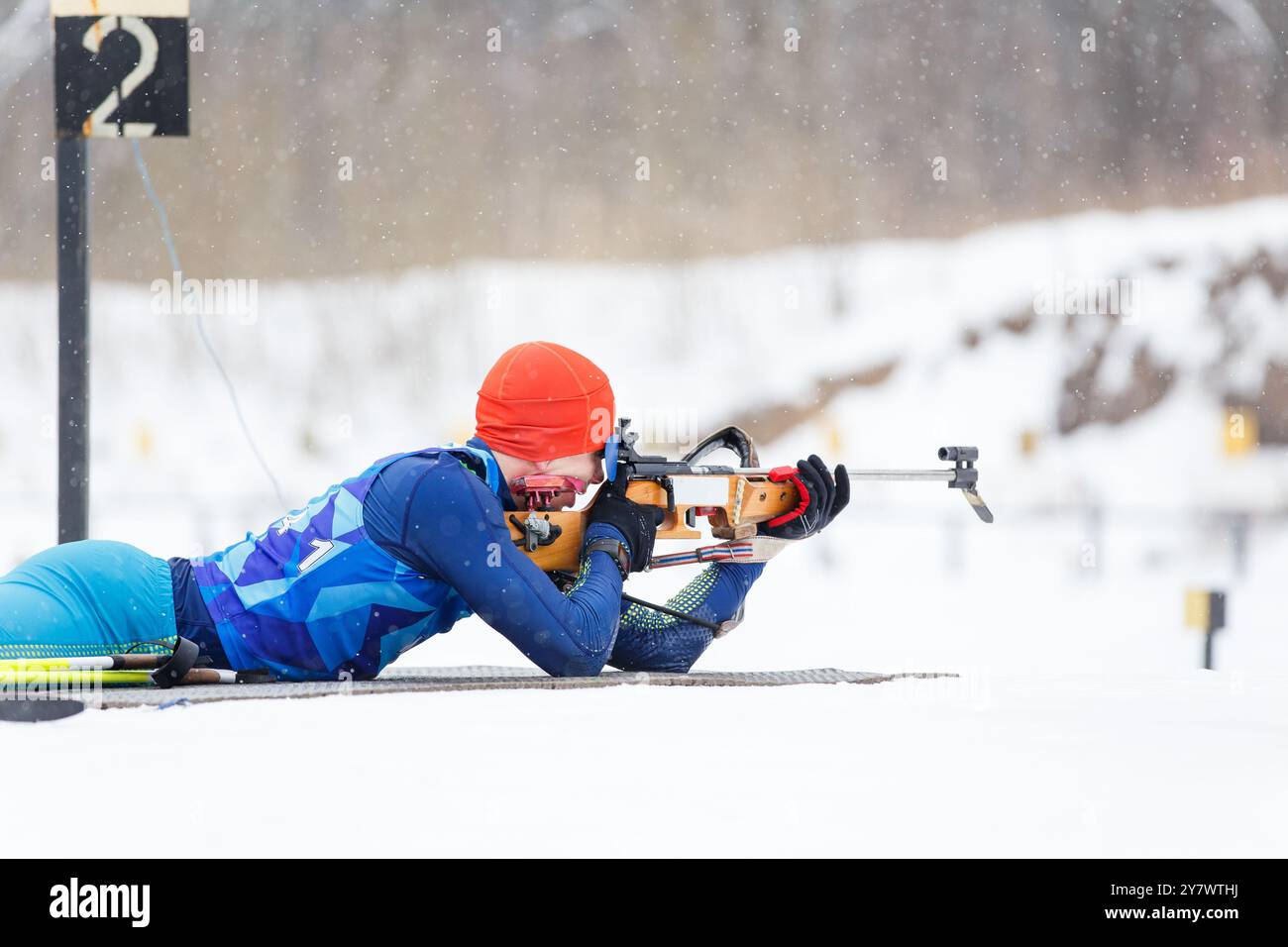 Athlete shooting in prone position at the range in a biathlon ...