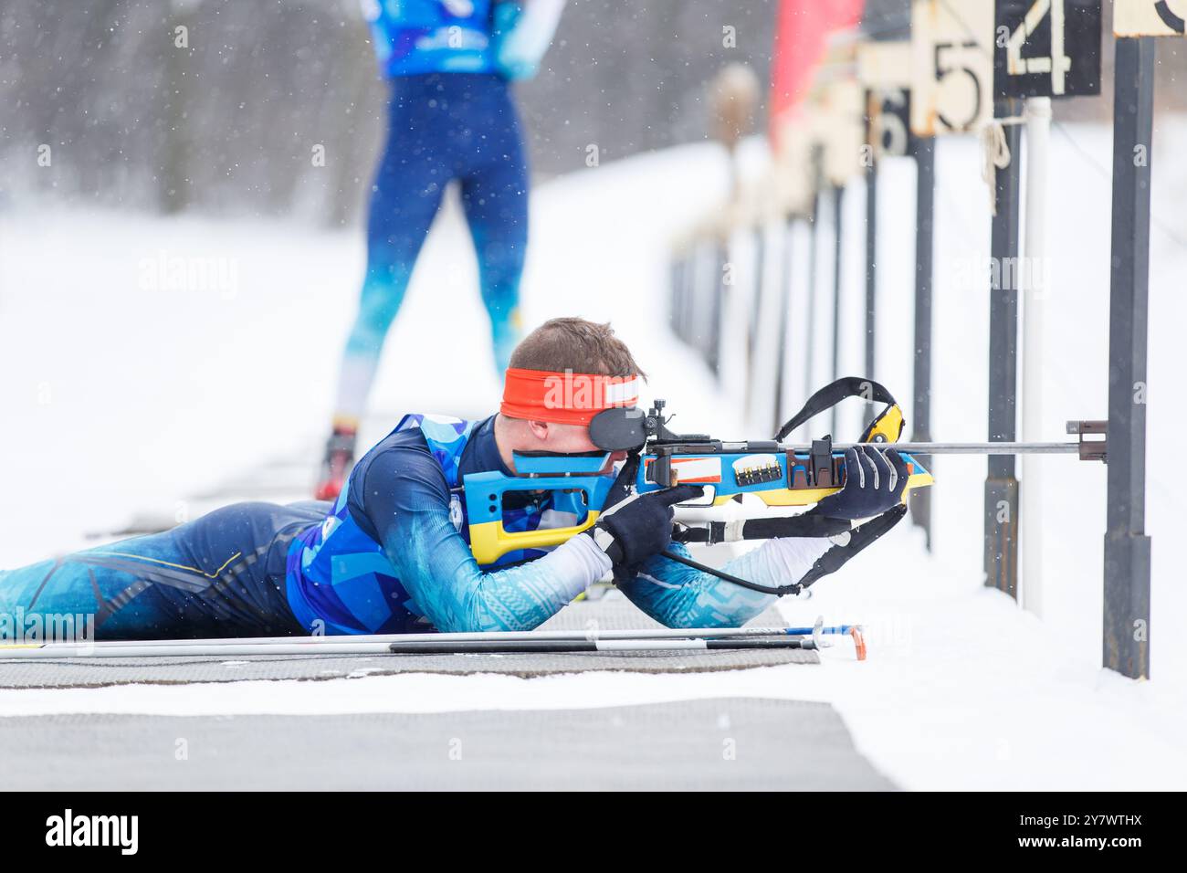 Athlete shooting in prone position at the range in a biathlon ...