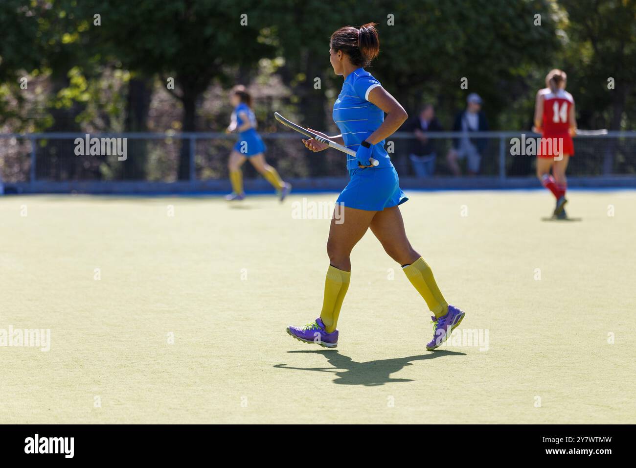 Young black field hockey player running with the stick on the turf ...