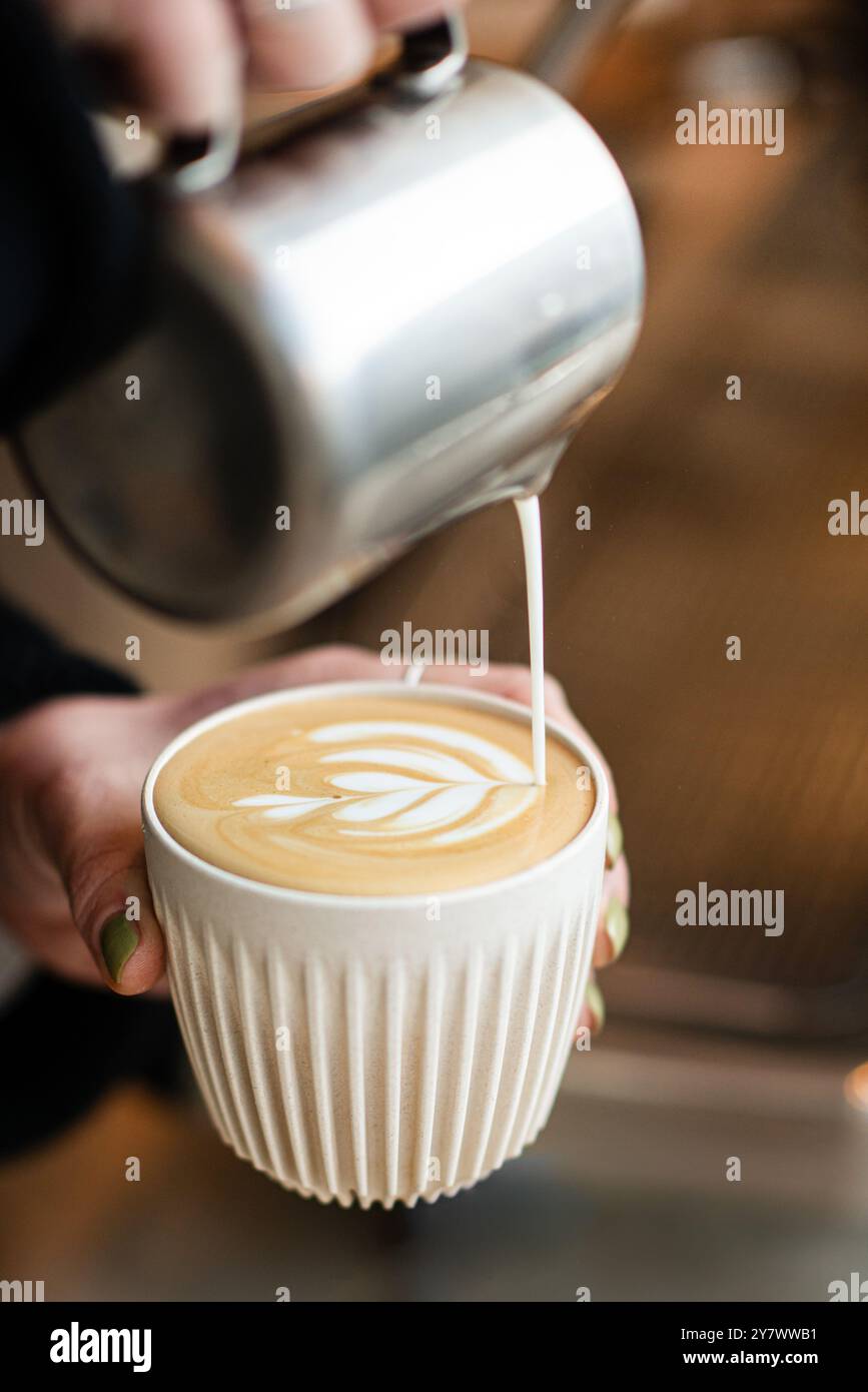 Female hands pouring milk and preparing fresh cappuccino. Coffee artist ...