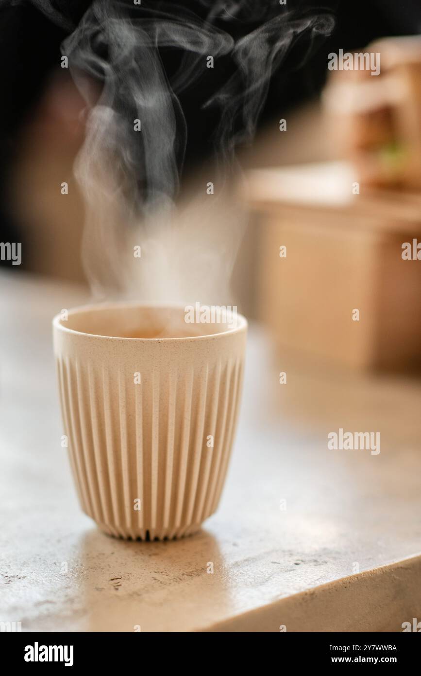 Steaming cup of coffee in a minimalist coffee shop. Side view Stock ...