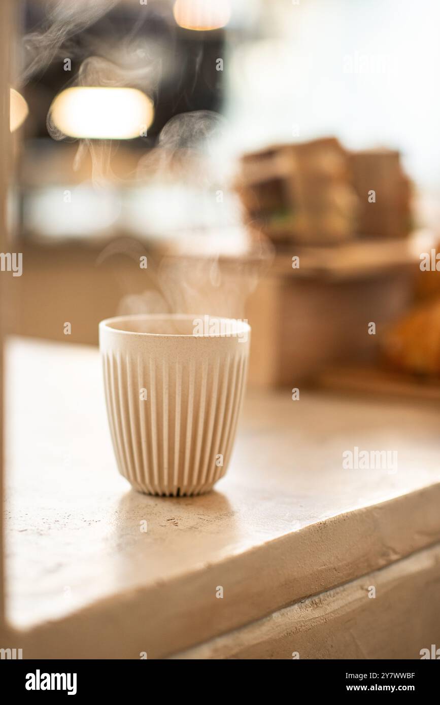 Steaming cup of coffee in a minimalist coffee shop. Side view Stock ...