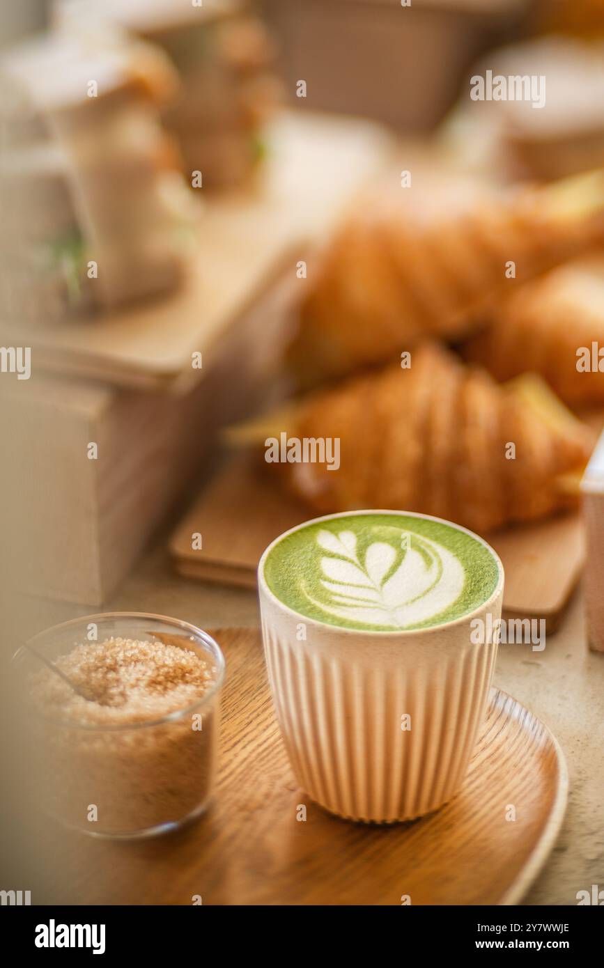 Cup of matcha latte surrounded by delicious pastries, in a coffee shop ...