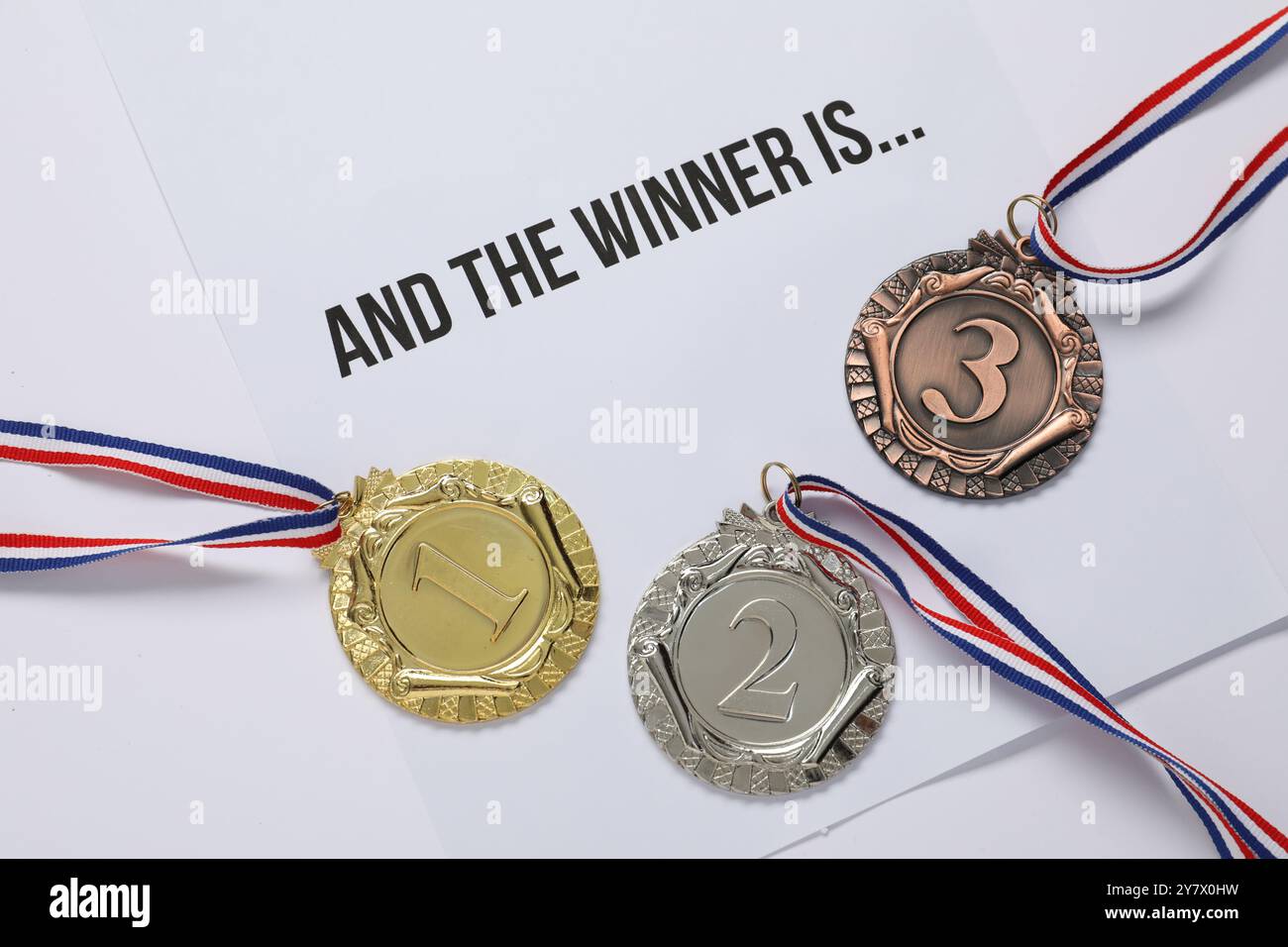 Sheet of paper with phrase And the winner is and different medals on ...