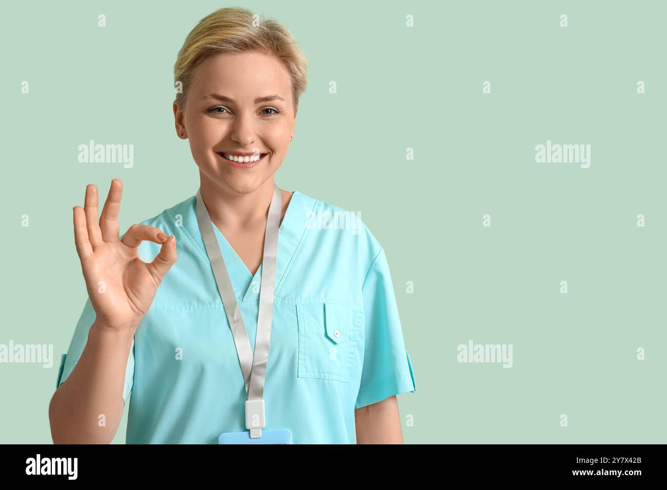 Female medical intern showing OK on green background Stock Photo - Alamy