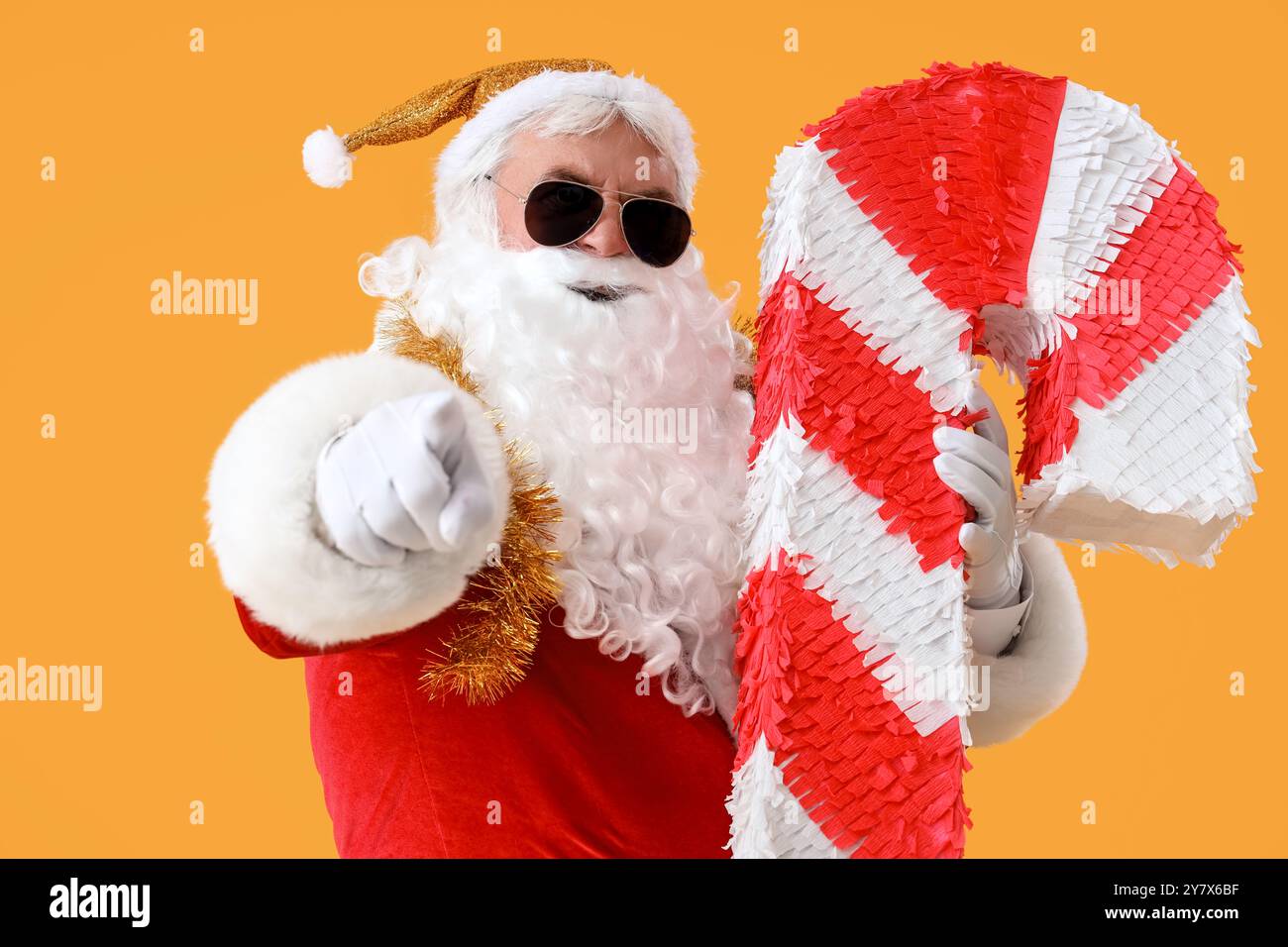 Cool Santa Claus with candy cane pinata pointing at viewer on yellow ...