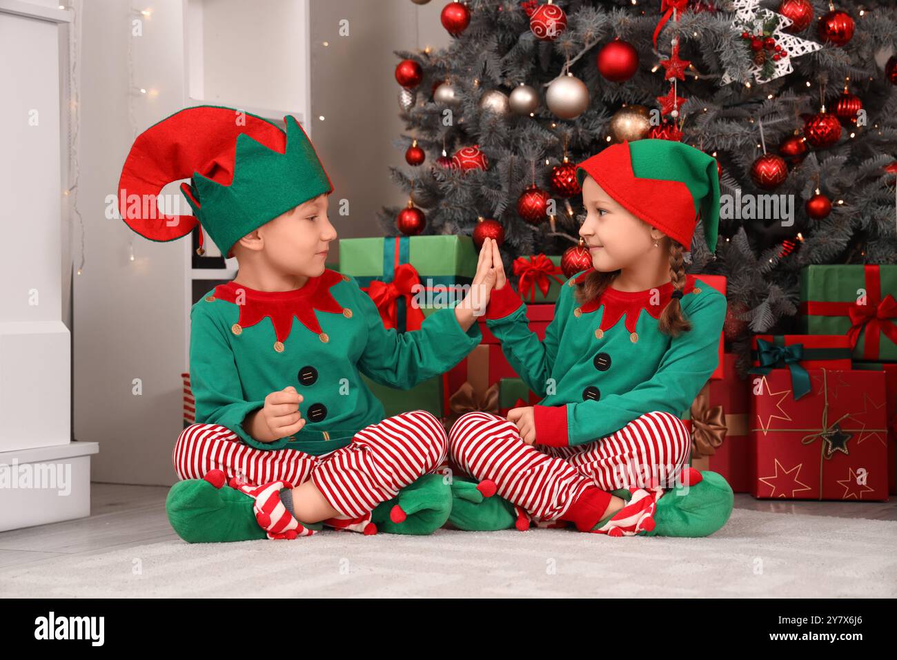 Cute little children in elf costumes giving each other high-five at ...