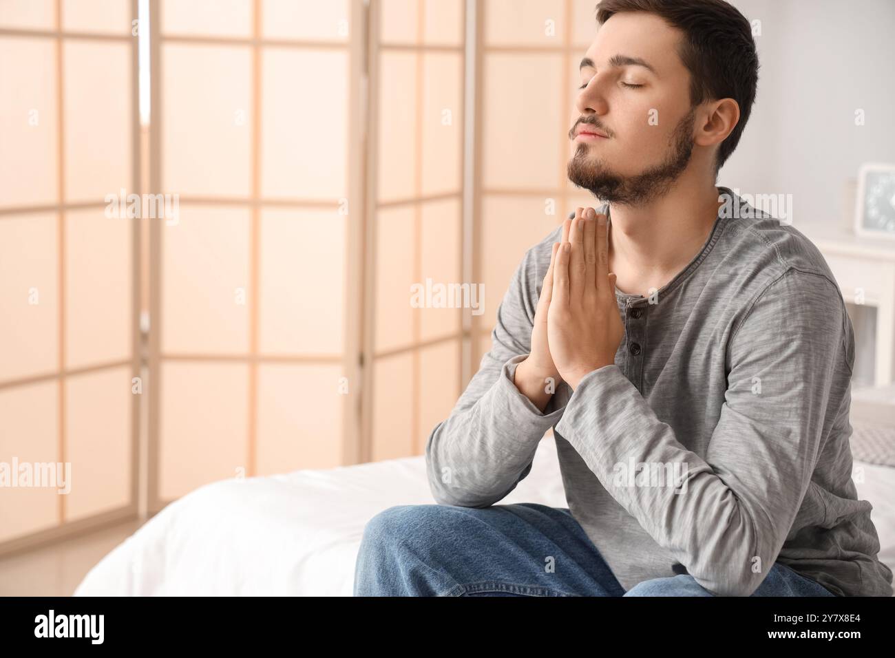 Young man praying in bedroom Stock Photo - Alamy