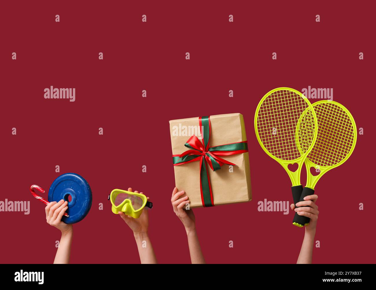Female hands holding candy cane, weight disc, present and tennis ...