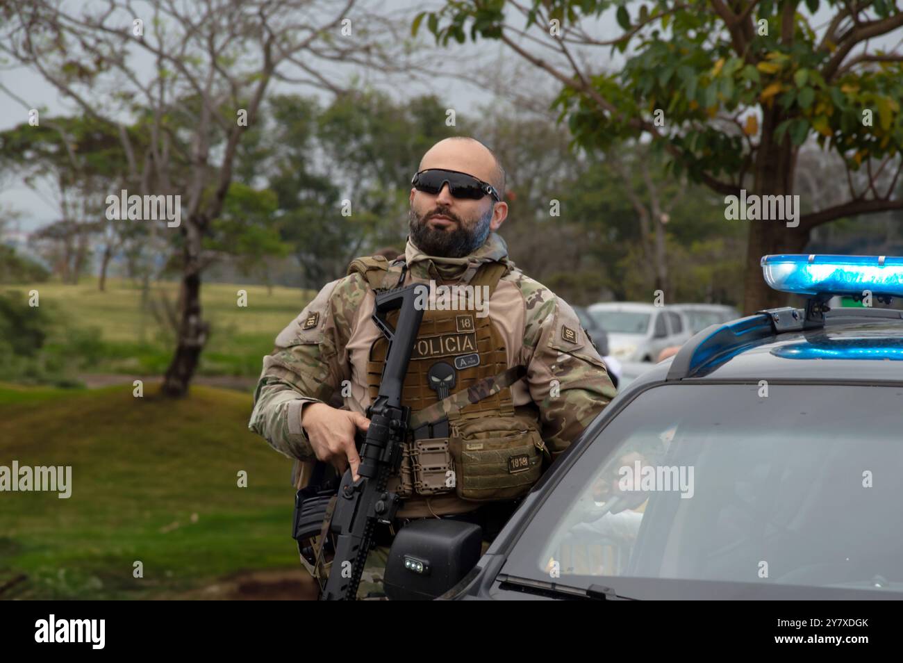 A police officer in camouflage clothing holding a gun with his body out ...