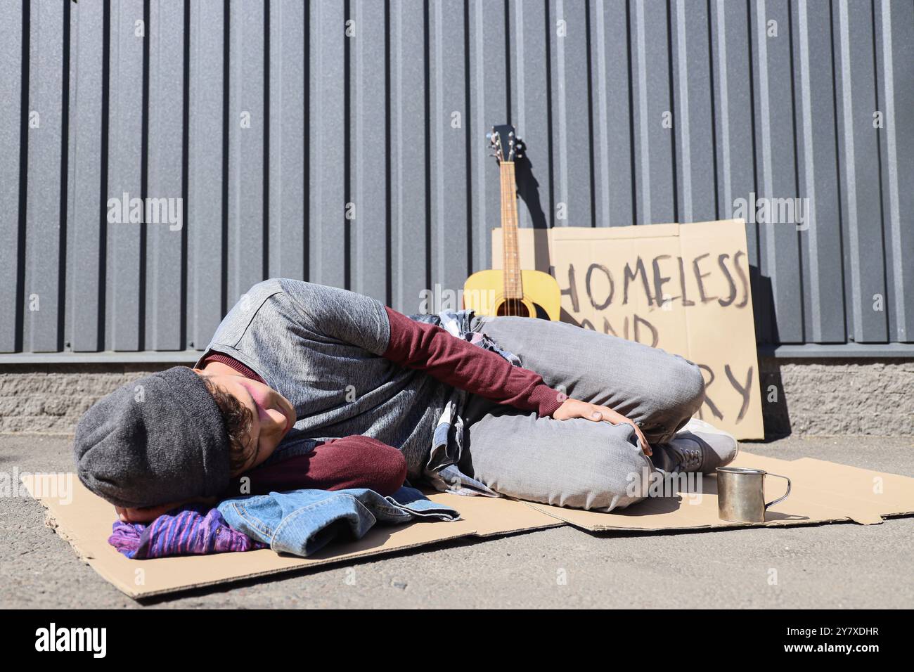 Young homeless man sleeping on street Stock Photo - Alamy