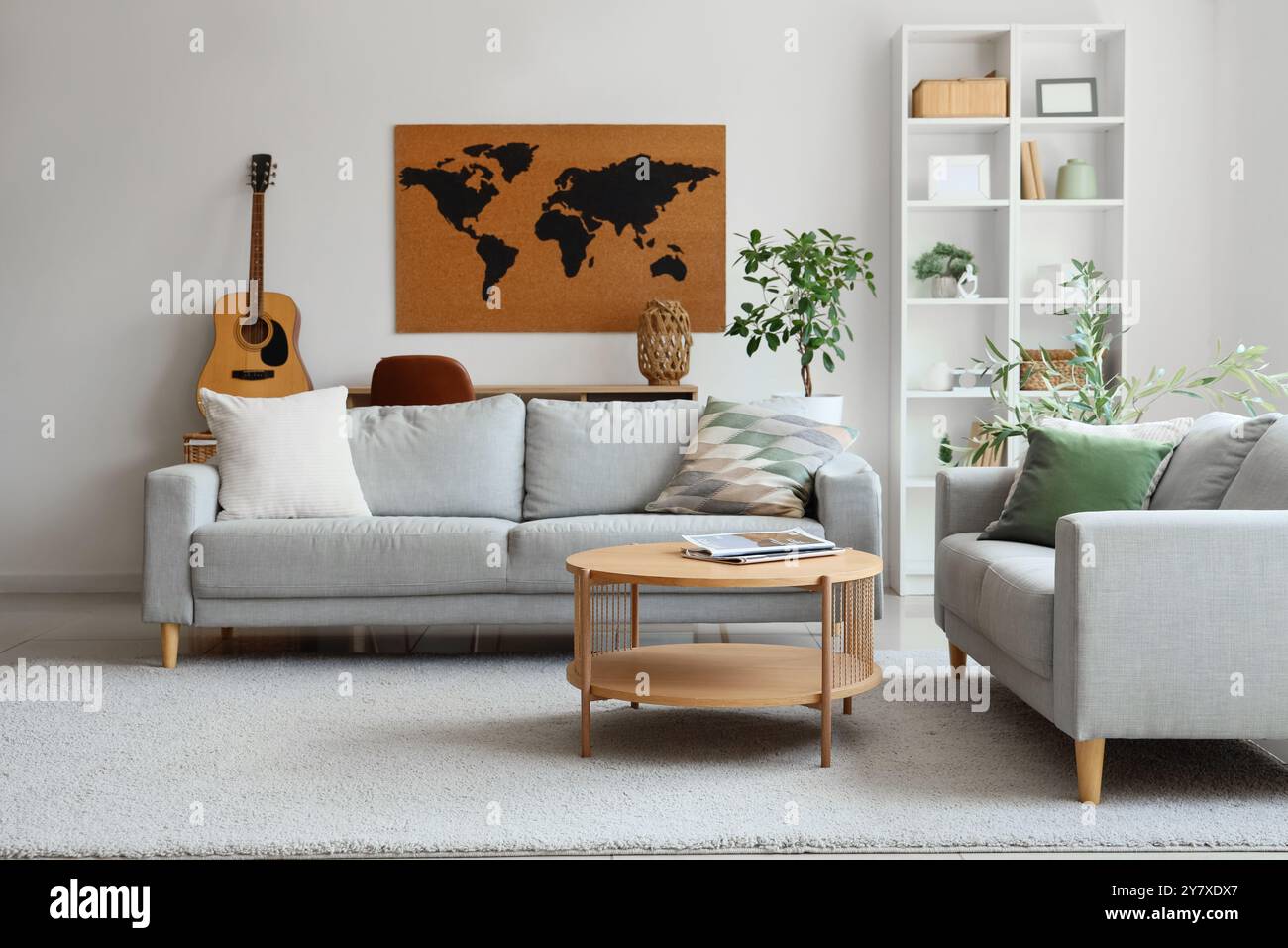 Sofa, table, shelving unit and world map on white wall in interior of ...