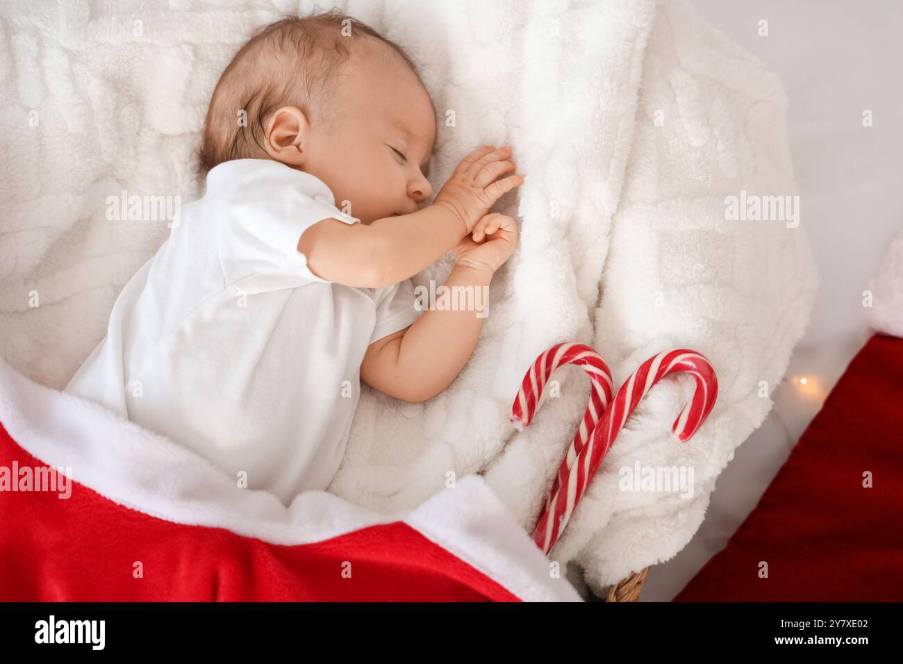 Cute little baby with candy canes sleeping in basket on Christmas eve ...