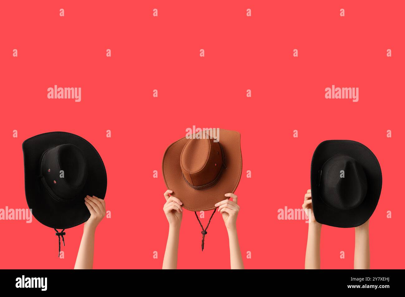 Female hands with cowboy hats on red background Stock Photo - Alamy