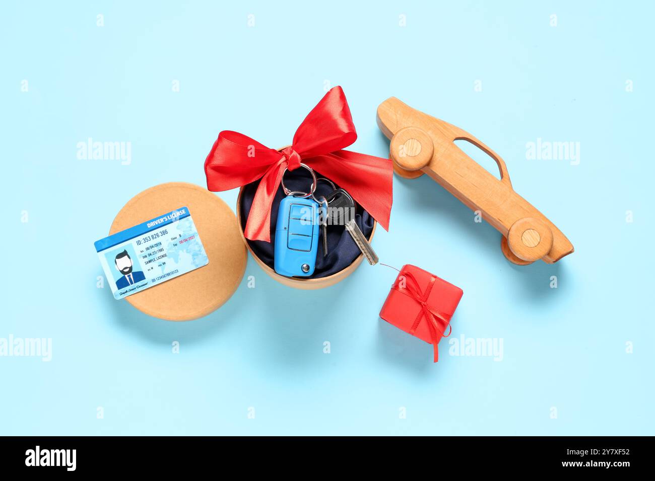 Gift box with keys of new car, driver license and wooden toy on color ...