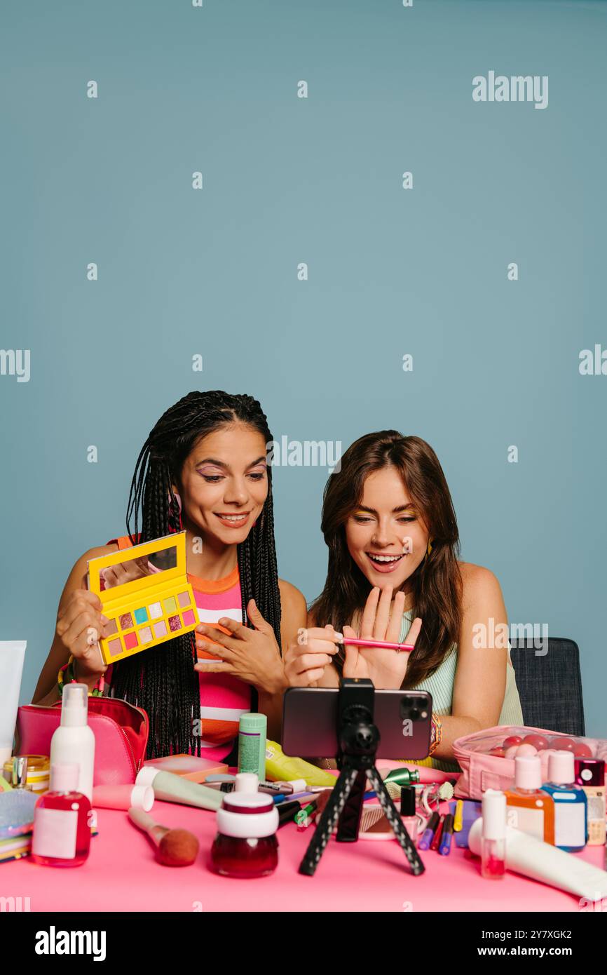 Two confident female presenters streaming beauty vlog while sitting at ...