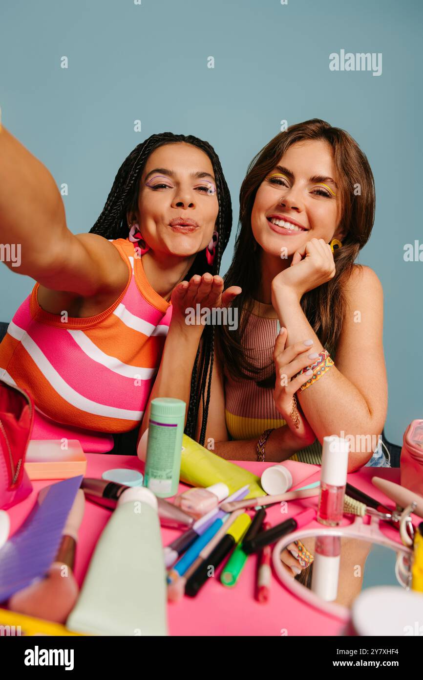 Two attractive female beauty vloggers making selfie while sitting at ...