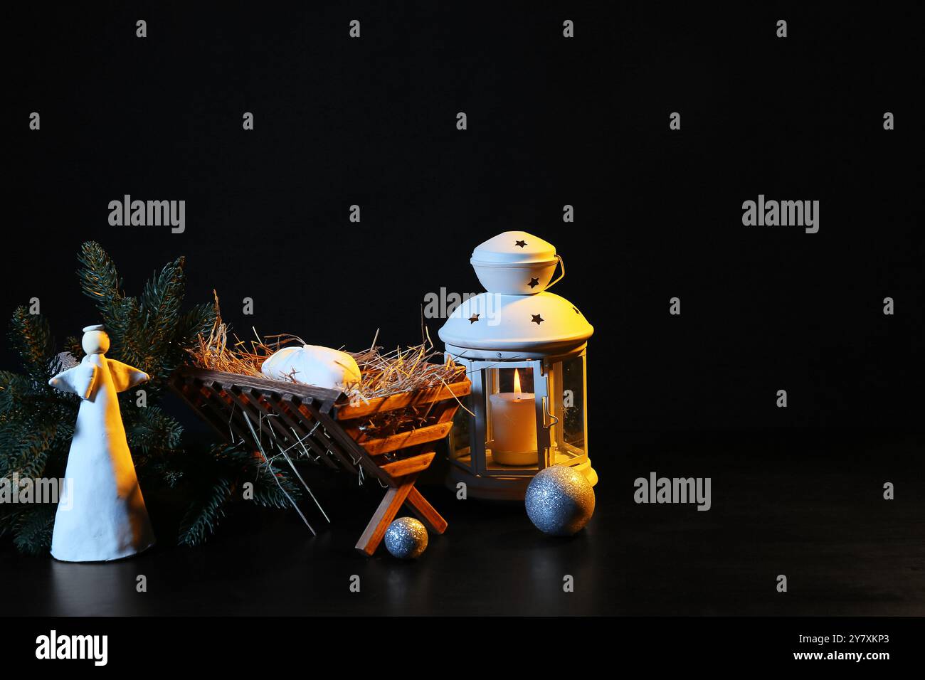 Manger with baby, angel, lantern and fir branches on dark background ...