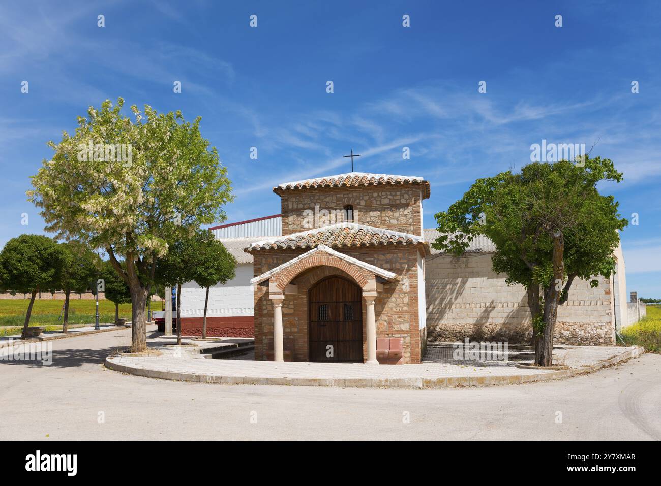 Small stone church with wooden door, flanked by trees under a clear ...