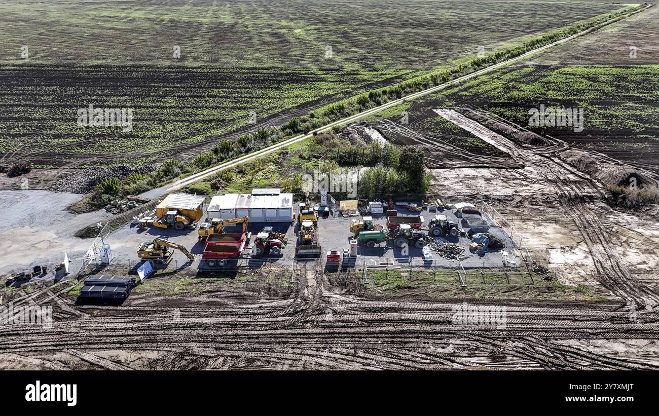 Construction vehicles are parked at an access road under construction ...