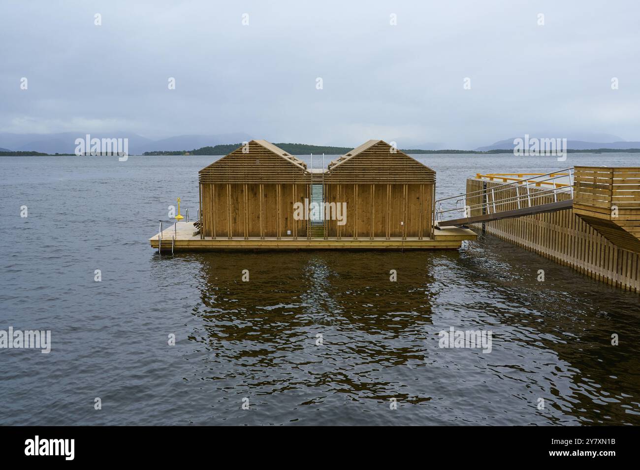 Outdoor sea pool by the fjord with small wooden sauna huts, overcast ...