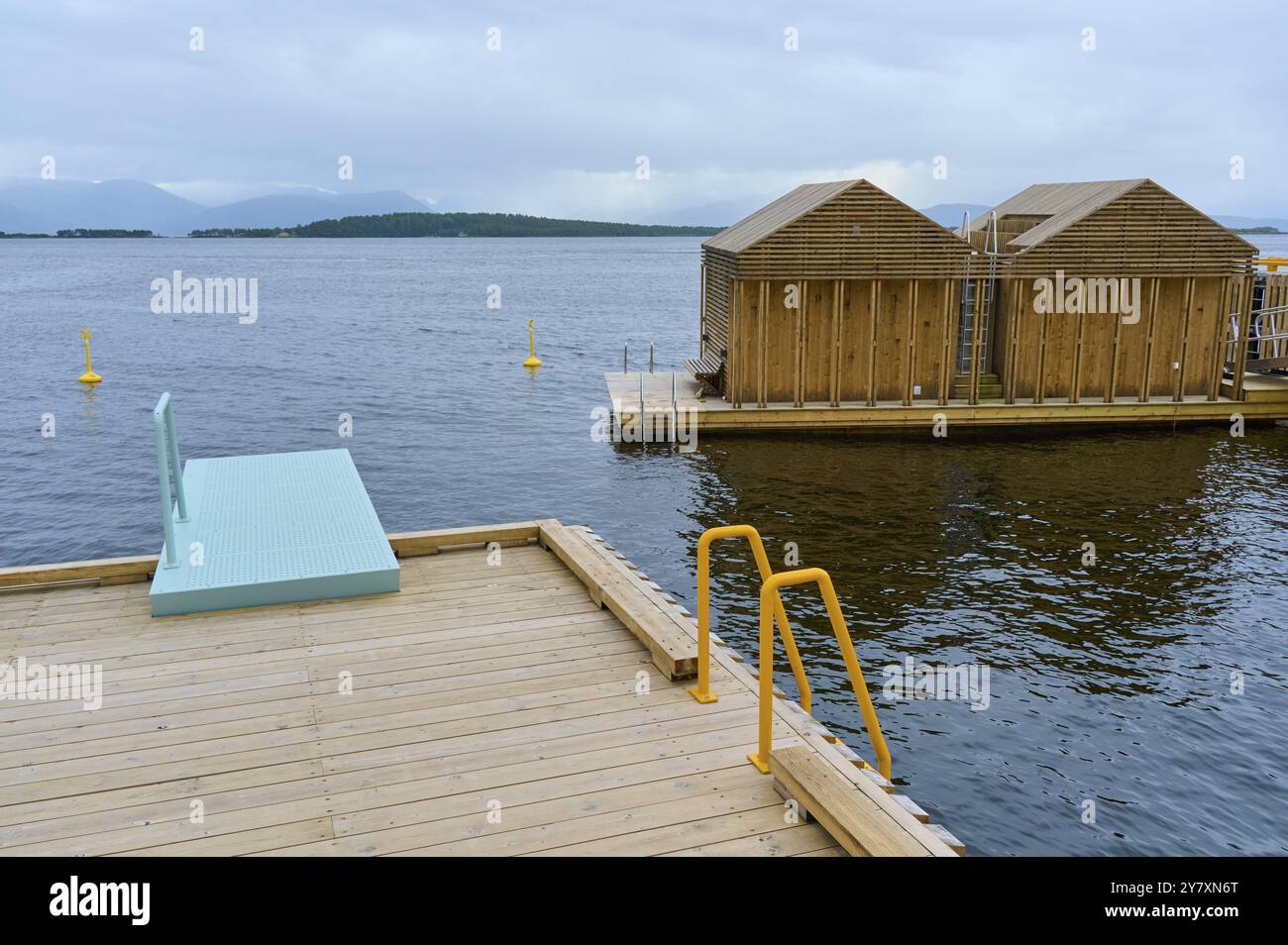 Seaside outdoor pool by the fjord with small wooden sauna huts ...