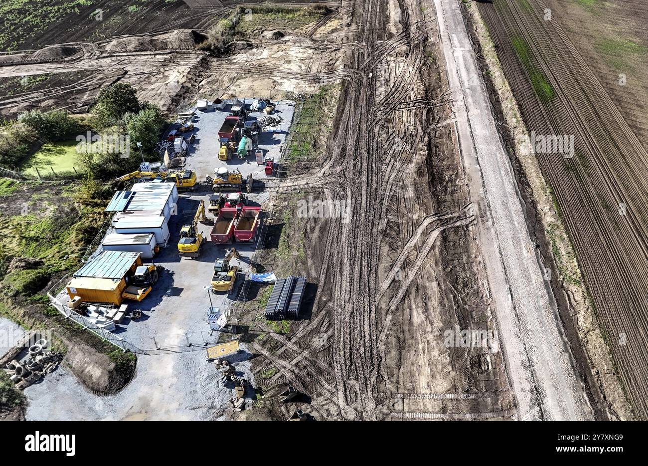 Construction vehicles are parked at an access road under construction ...