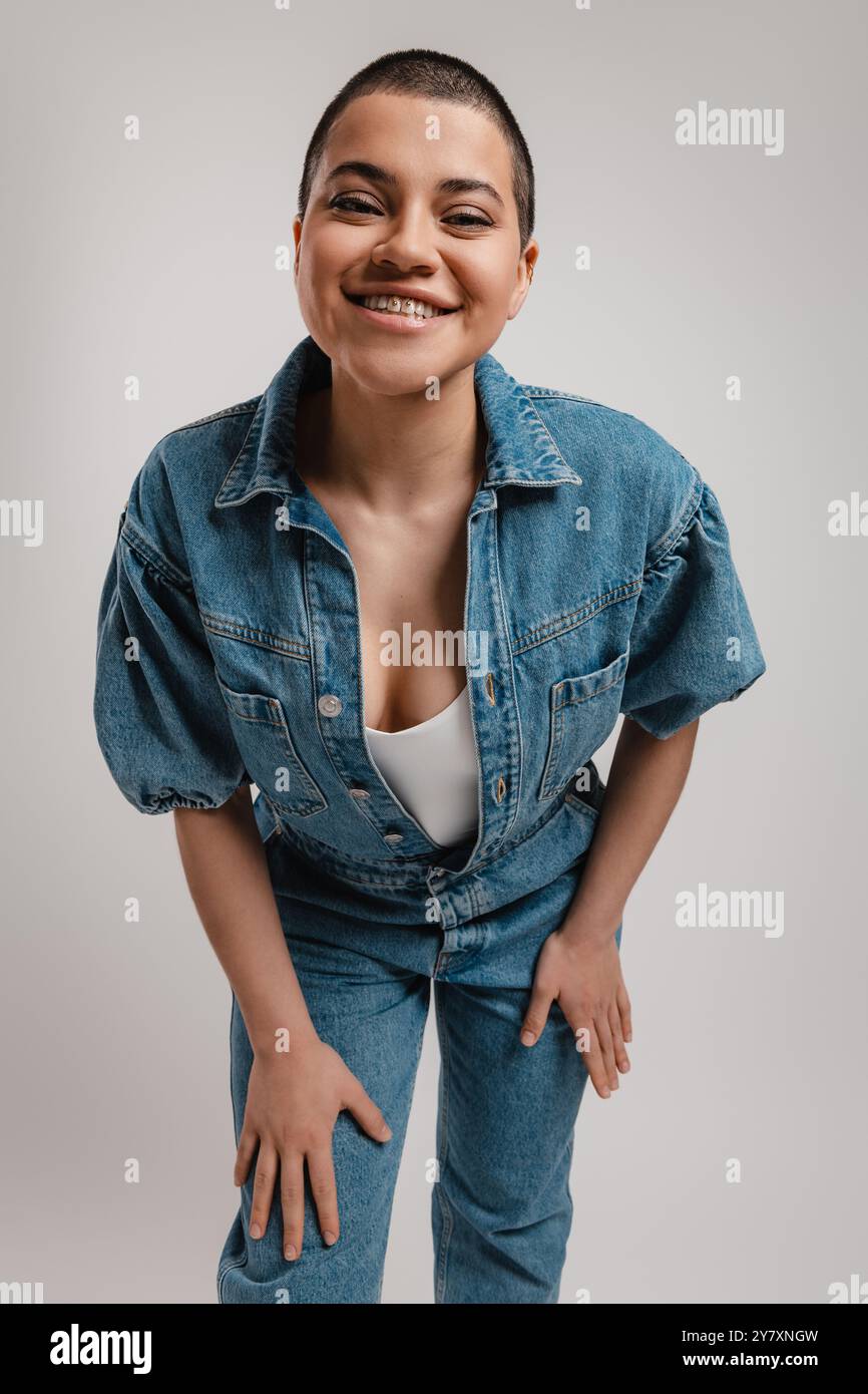 Happy short hair woman in denim clothes looking at camera against grey ...
