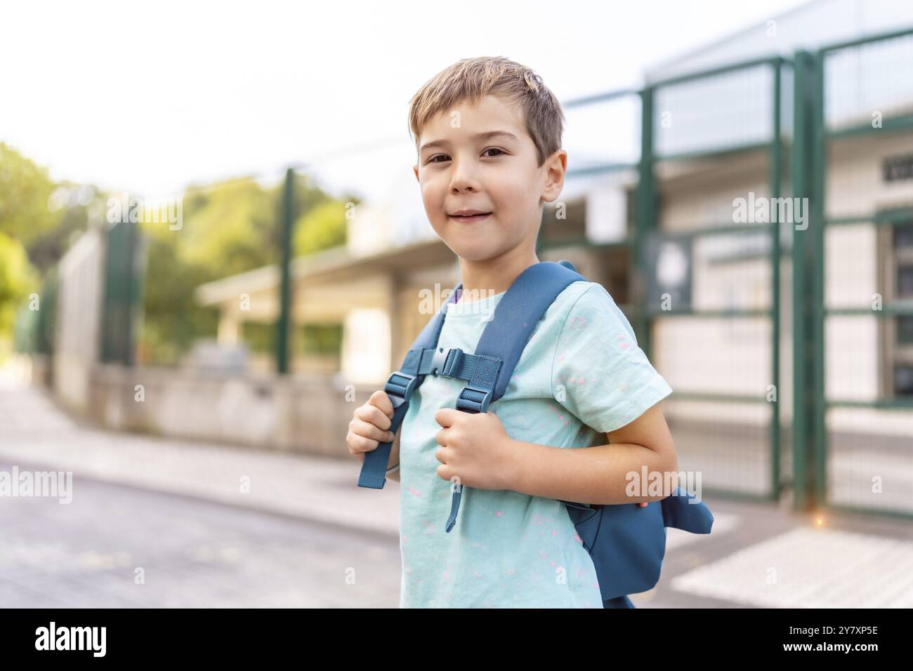 Portrait of a proud boy smiling at camera standing next to school ...